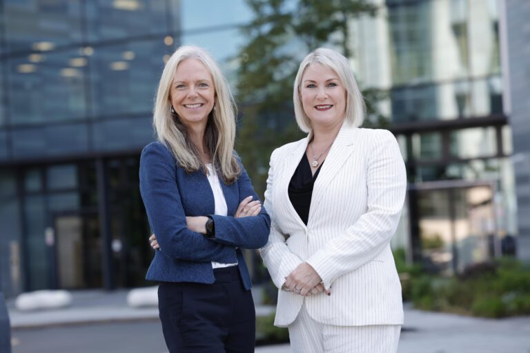 Two people standing in front of a corporate building