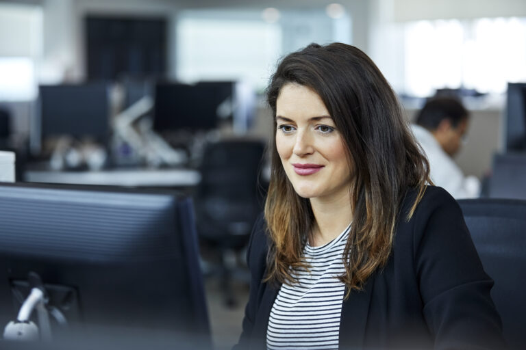 Smiling businesswoman using computer at desk. Female executive is wearing smart casuals. She is working in office.