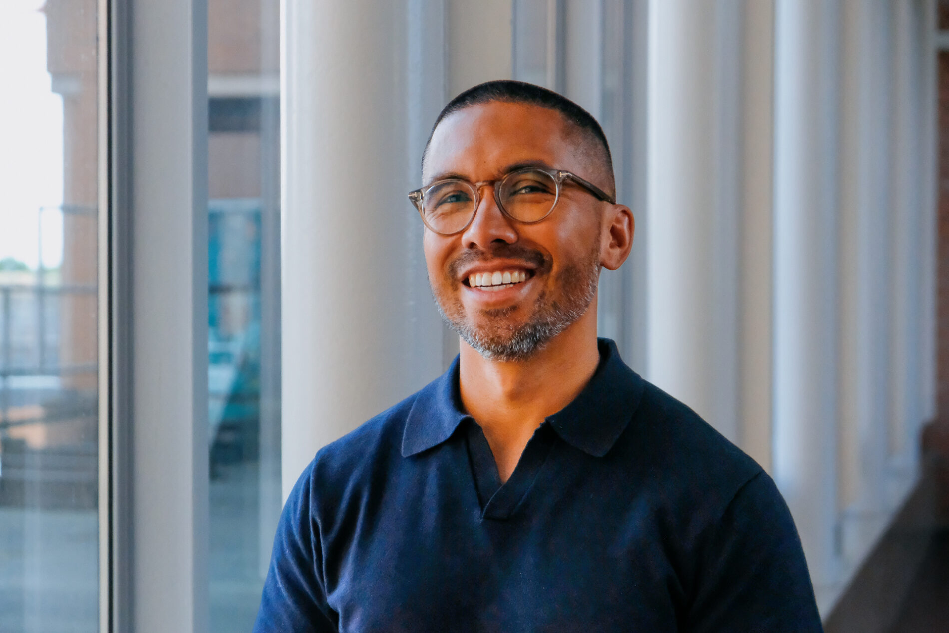 Portrait of a smiling man with glasses. He’s wearing a blue polo shirt.