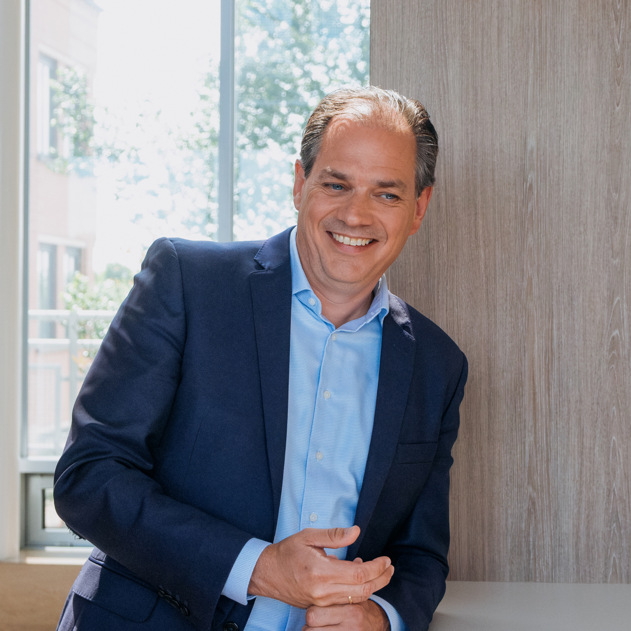 Portrait of smiling man in a blue suit leaning on a counter.